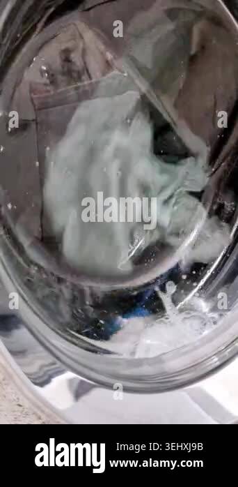 Vertical, close-up view of clothes spinning vigorously in a front ...