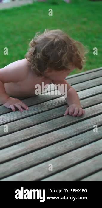 Young child stepping off outdoor chair near calm lake park highlighting ...