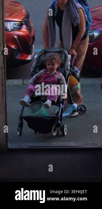 Mother arrives home pushing child in stroller through entrance ...