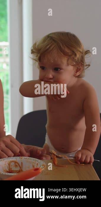 Young child turns away from pasta while parent continues feeding effort ...
