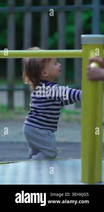 Siblings turning around on playground roundabout during outdoor ...