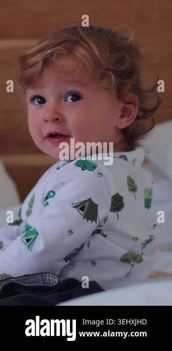 Young child balances on soft bed while distracted by something off ...