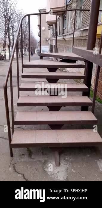 Outdoor metal spiral staircase with tiled steps on an urban sidewalk ...