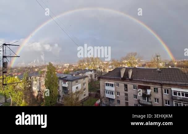 Vivid rainbow forms a complete arch over a residential cityscape with ...