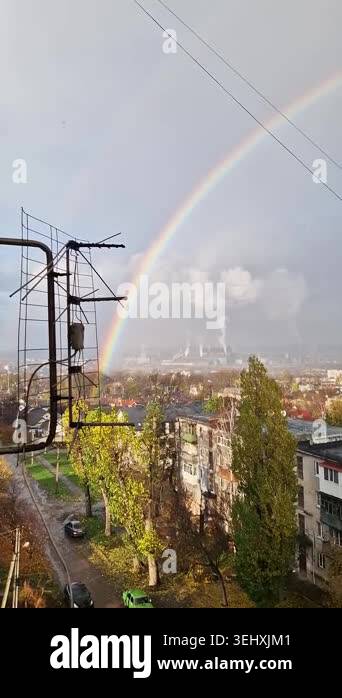 Double rainbow appears in the sky over a city after rain, with an ...
