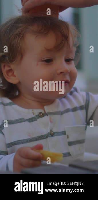 Mother joking with child at restaurant table using small object during ...
