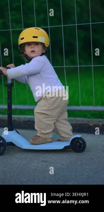 Young child pauses beside scooter and looks ahead, capturing stillness ...