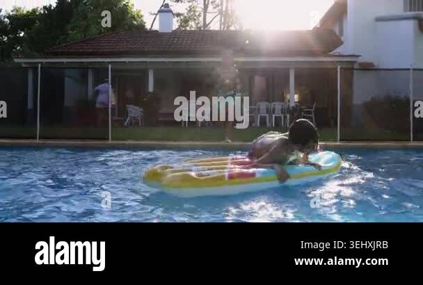 Boy sprinting and diving into backyard pool with explosive splash as ...