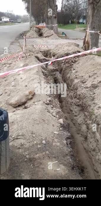 A deep earthen trench is dug for utility pipes or cables within an ...