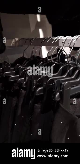 Row of black clothing with shiny embellishments hangs on black hangers ...