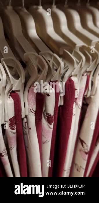 Children's pajamas hang in a neat row on white plastic hangers in a ...