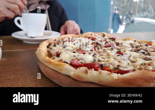 Hot pizza with melted cheese, mushrooms, and sausage sits on a wooden ...