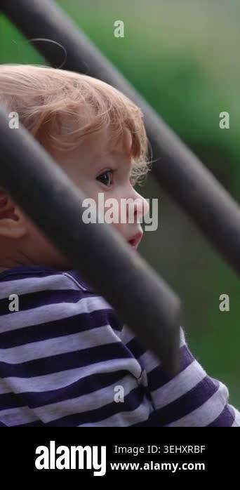 Young child exploring elevated play equipment at playground while ...
