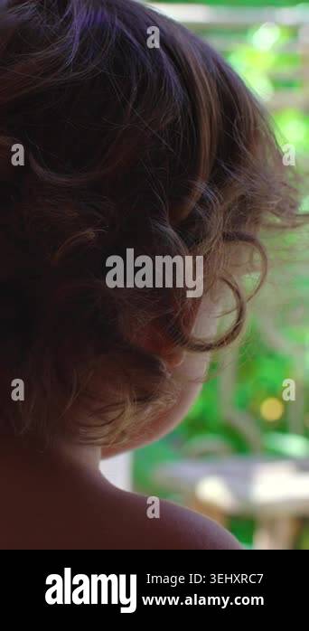 Young child stands quietly near open door while observing outdoor light ...