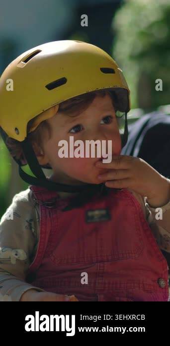 Young child wearing protective helmet eats fresh tangerine outside ...