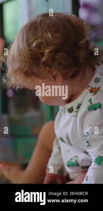 Young child examines toy car garage while playing independently at home ...