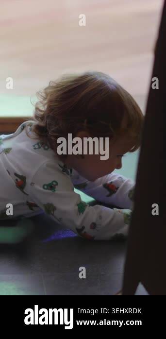 Young siblings play together indoors as older child steadies toddler ...