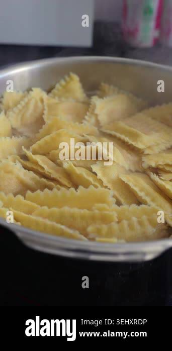 Uncooked filled pasta simmering in hot water inside kitchen pot ...