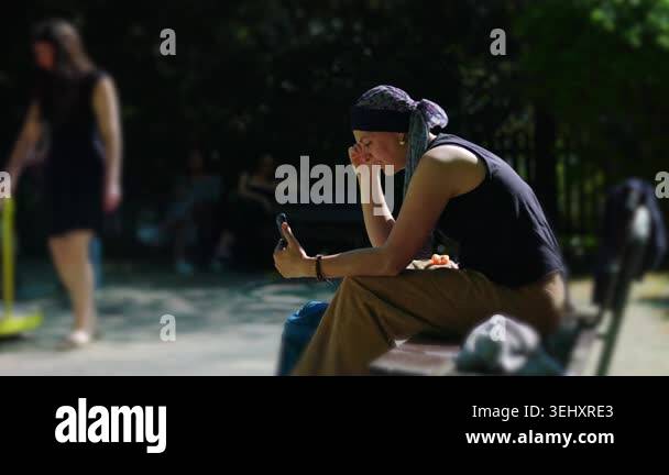 Headscarf woman talks on a video call while resting in a park ...