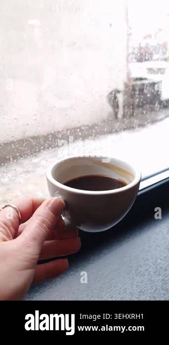 Close-up of a hand holding a white mug filled with black coffee against ...