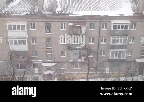 A weathered brick apartment building stands covered in fresh snow ...
