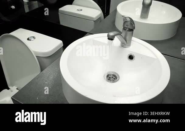Modern white ceramic sink with fresh water flowing from a chrome faucet ...