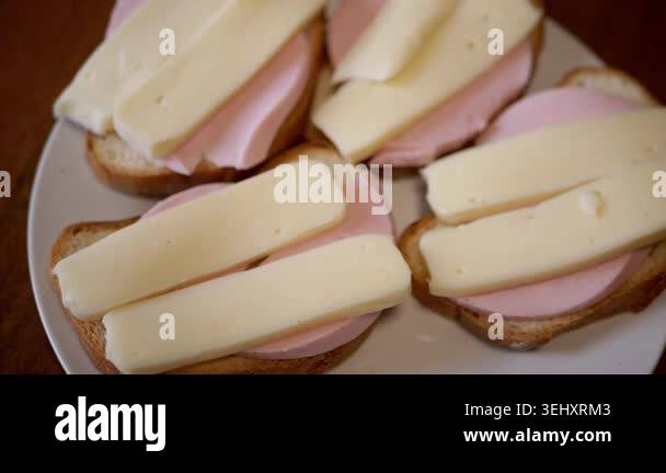 Four slices of bread topped with pink sausage and thick yellow cheese ...