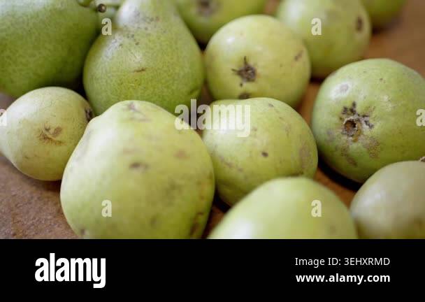 Fresh green pears scattered on a wooden table surface in slow motion ...