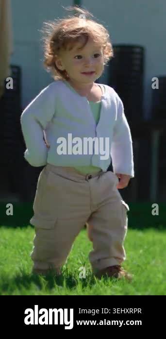 Young child moving confidently through green park lawn in warm daylight ...