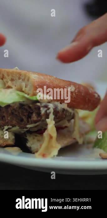 Closeup of female customer enjoying juicy artisan burger while dining ...