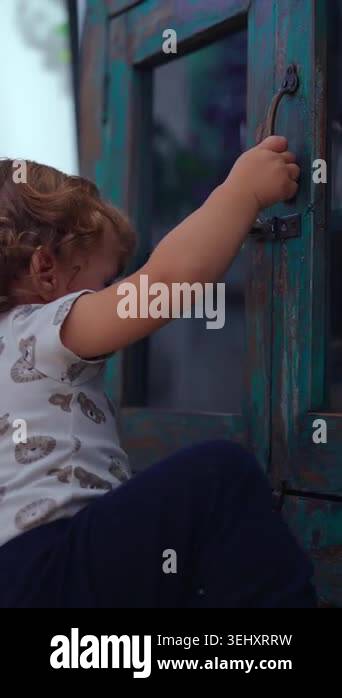 Young child examining vintage furniture doors in comfortable living ...