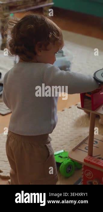Young child observing brother playing with miniature vehicles in cozy ...