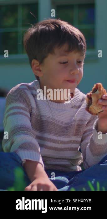 Boy relaxing outdoors with picture book and burger near family ...