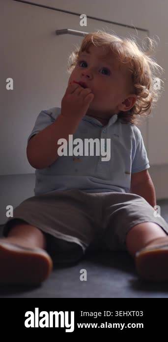Young child resting on kitchen floor in cozy domestic interior creating ...