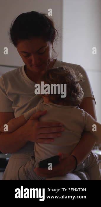 Pensive parent holding young child indoors symbolizing caregiving ...