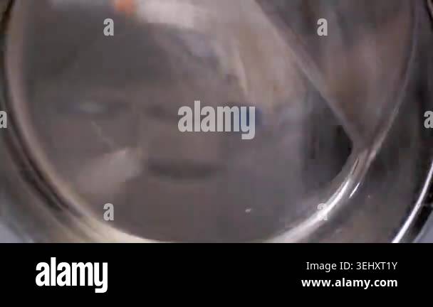 Close-up inside a metal washing machine drum spinning a load of laundry ...