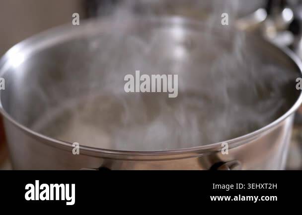Heavy white steam rises continuously from boiling hot water inside a ...