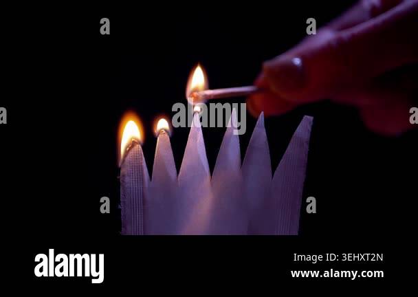 Female hand uses lit match to ignite jagged peaks of white paper cutout ...