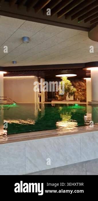 An indoor swimming pool features vibrant green water, an artificial ...