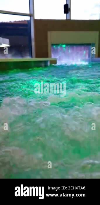 Green illuminated water bubbles and churns inside a modern indoor ...
