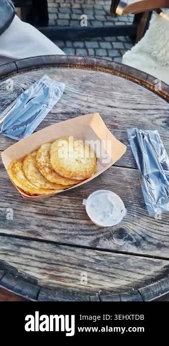 Golden brown potato pancakes sit in a cardboard tray next to creamy ...
