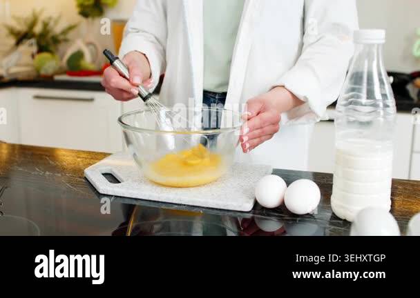 Unrecognizable woman whisking eggs in bowl for omelet breakfast in home ...