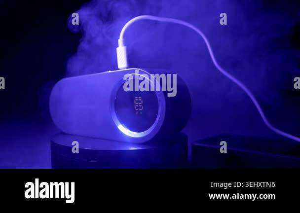 A portable humidifier charges via USB cable, releasing a steady stream ...