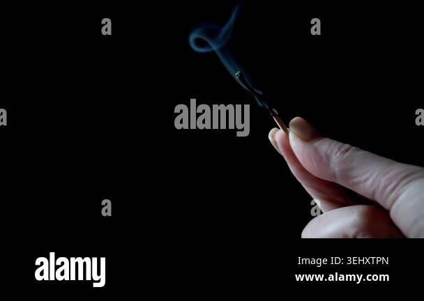 Person holds extinguished matchstick with grey smoke billowing upwards ...