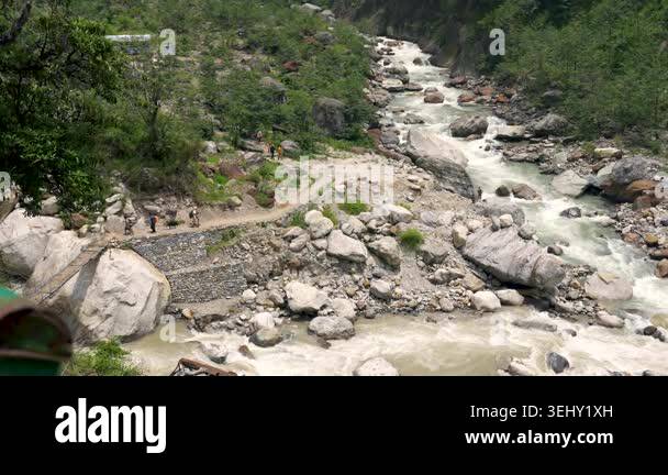 Dry riverbed with scattered rocks and sparse vegetation in a high ...