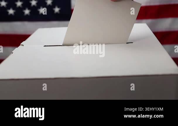 Hand inserting ballot into a white ballot box with the american flag ...