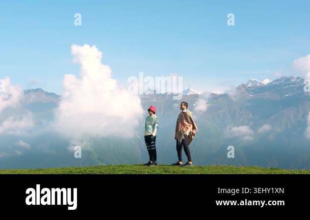 Two individuals observe the expansive Himalayan landscape from a green ...
