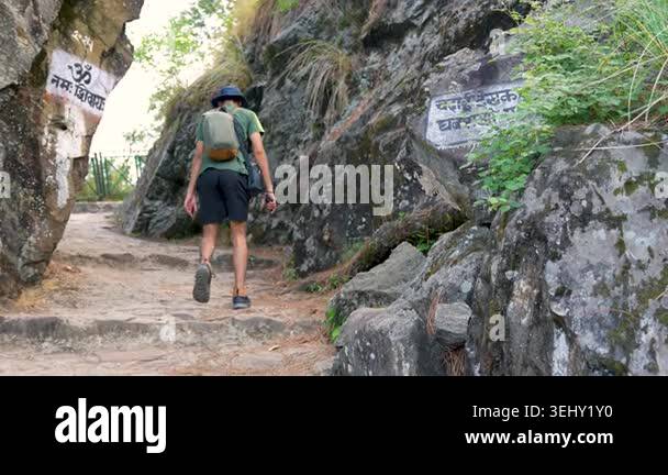 A person with a backpack treks along a narrow path surrounded by large ...