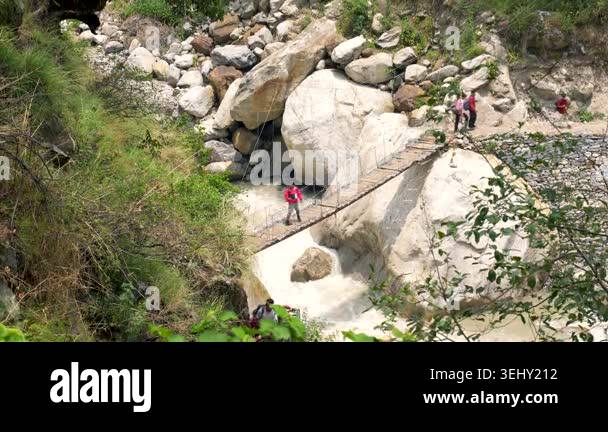 A person walks along a narrow path between large rocks and greenery on ...