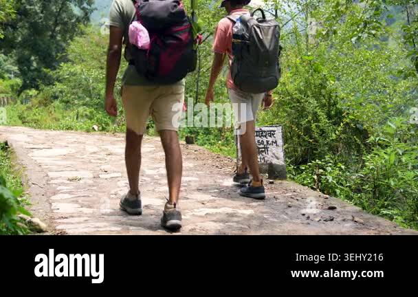 Person trekking along a mountain path with a directional sign in the ...